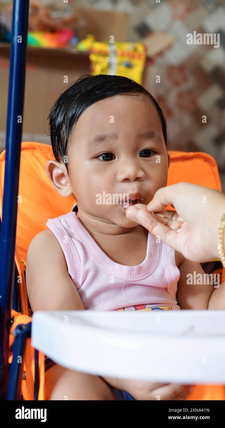 baby boy sitting on a swing chair, son's expression is cute while ...