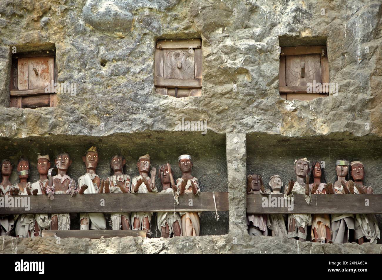 Stone grave openings and wooden effigies on a cliff at a traditional ...