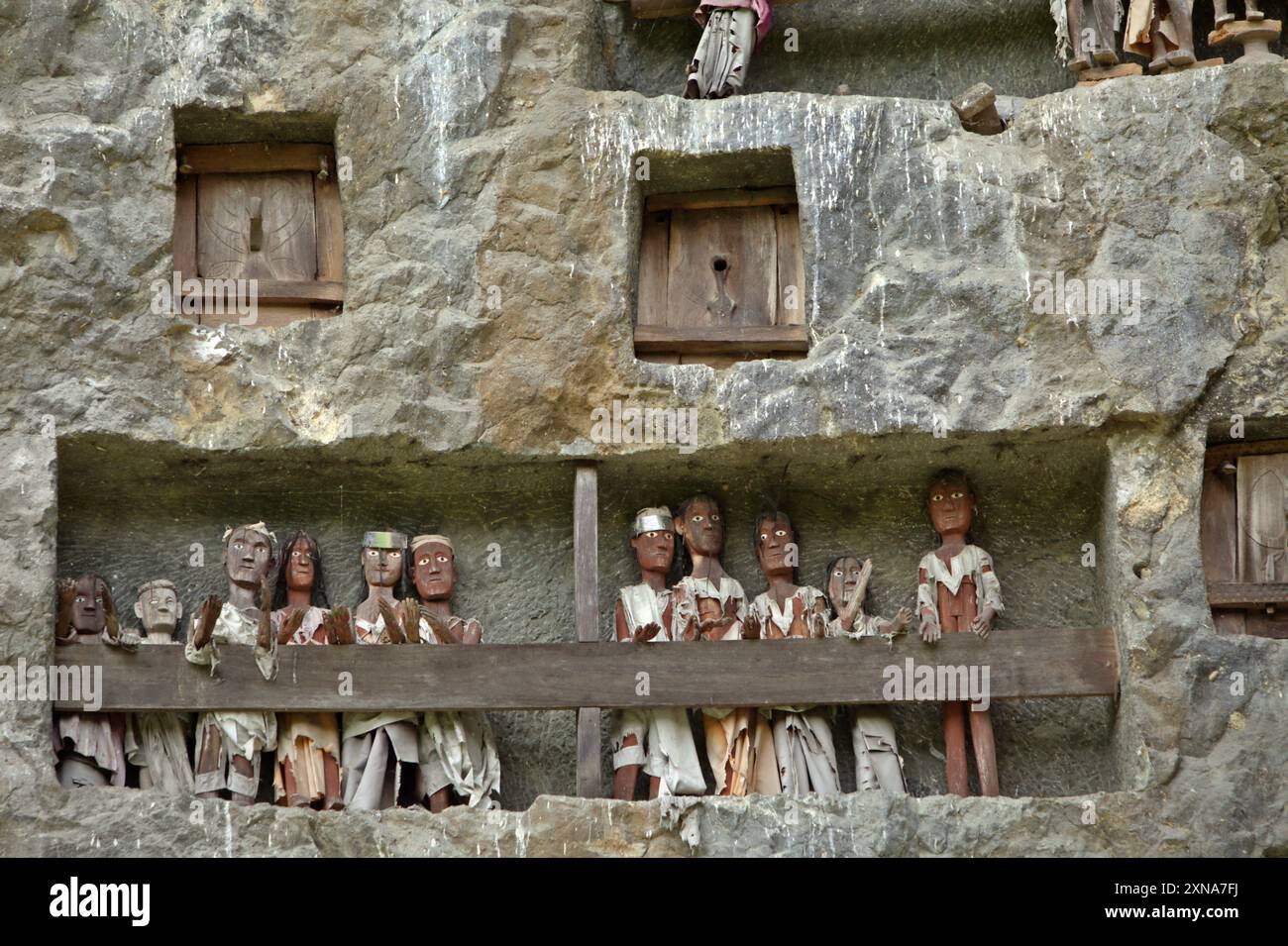 Stone grave openings and wooden effigies on a cliff at a traditional ...