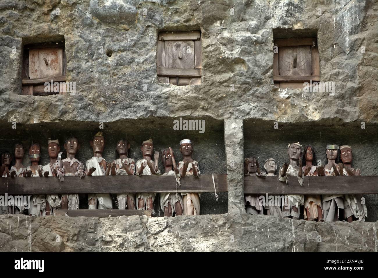 Stone grave openings and wooden effigies on a cliff at a traditional ...