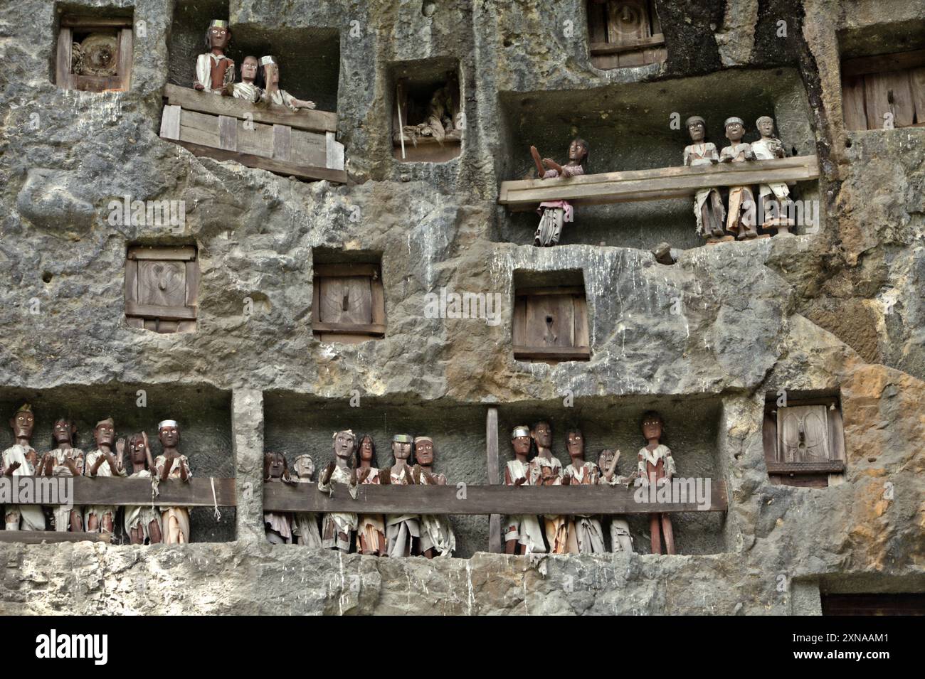 Stone grave openings and wooden effigies on a cliff at a traditional ...