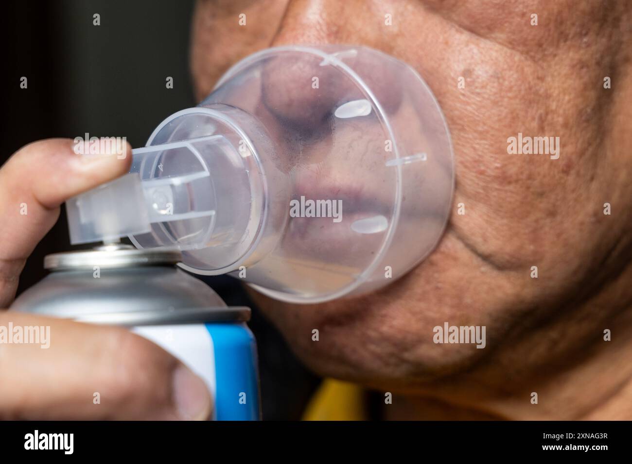 Closeup of elderly Asian man inhaling oxygen from cannister in high ...