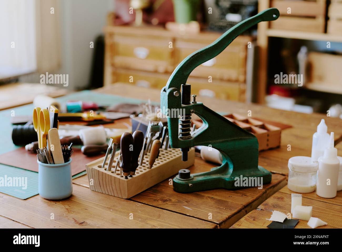 Medium close up of old metal leather punch machine surrounded by ...