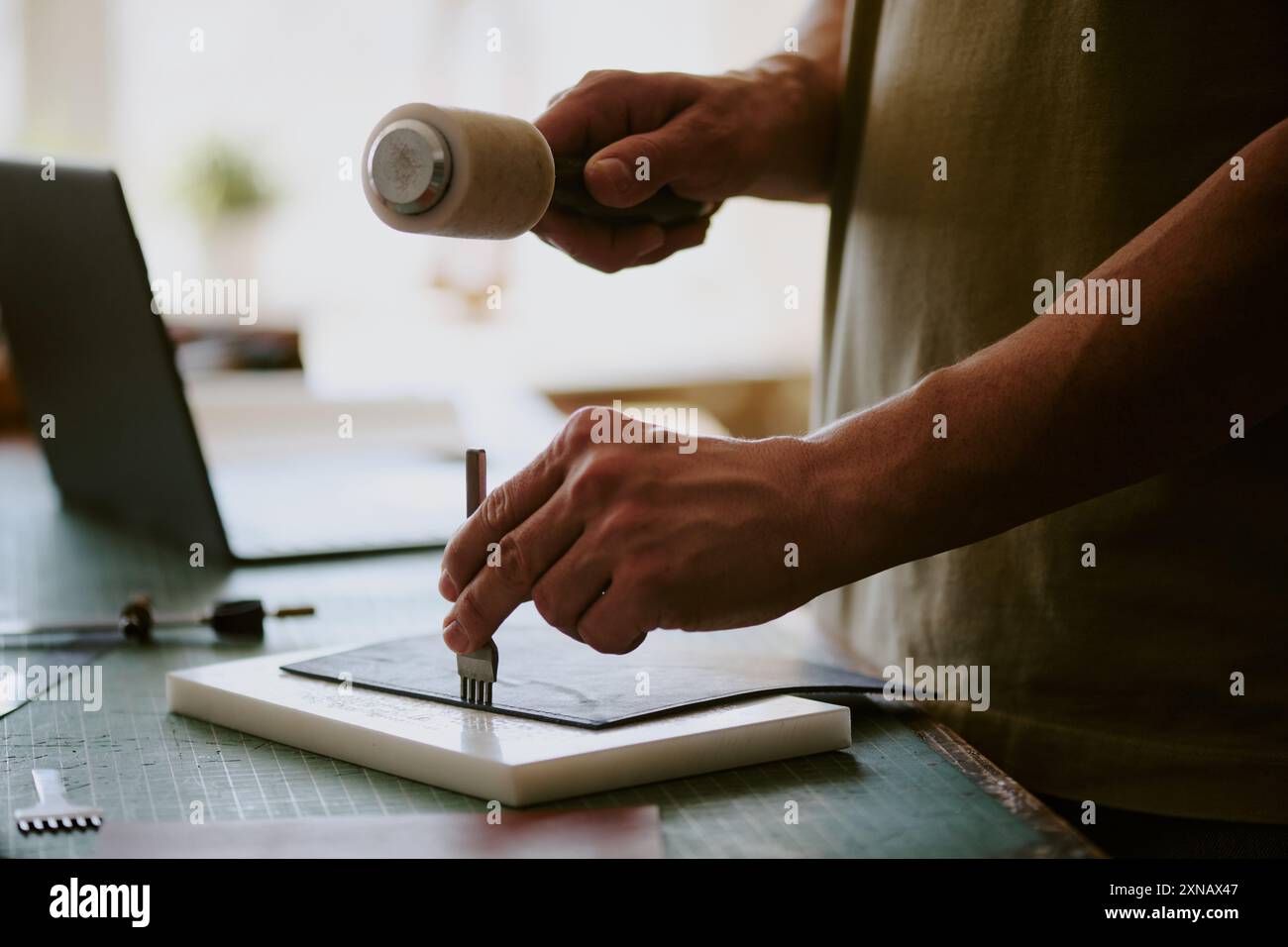Medium close up of strong male hands using leather punch to poke ...