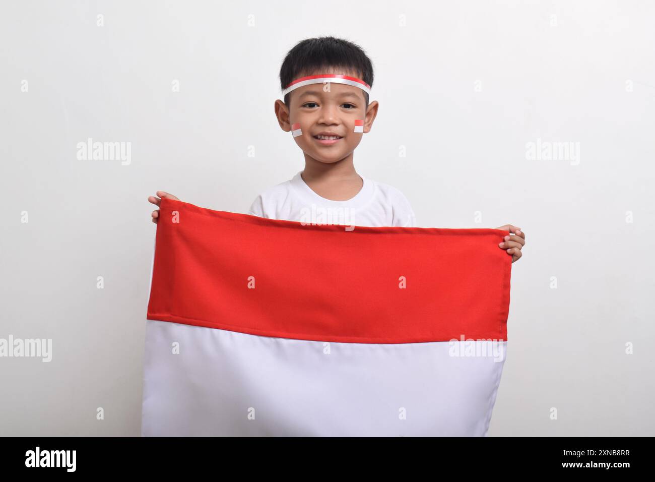 Asian boy wearing flag headband and holding Indonesian flag to ...