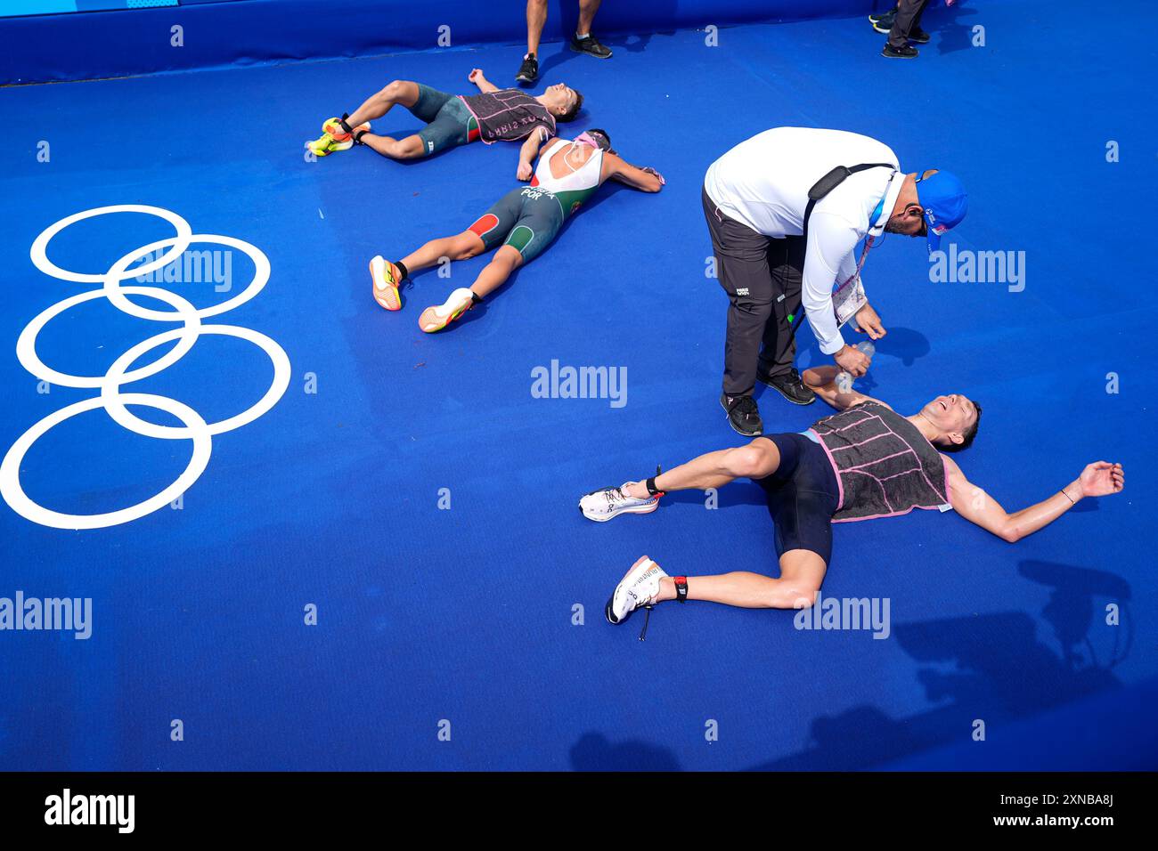 Athletes sit on the floor at the end of the men's individual triathlon ...