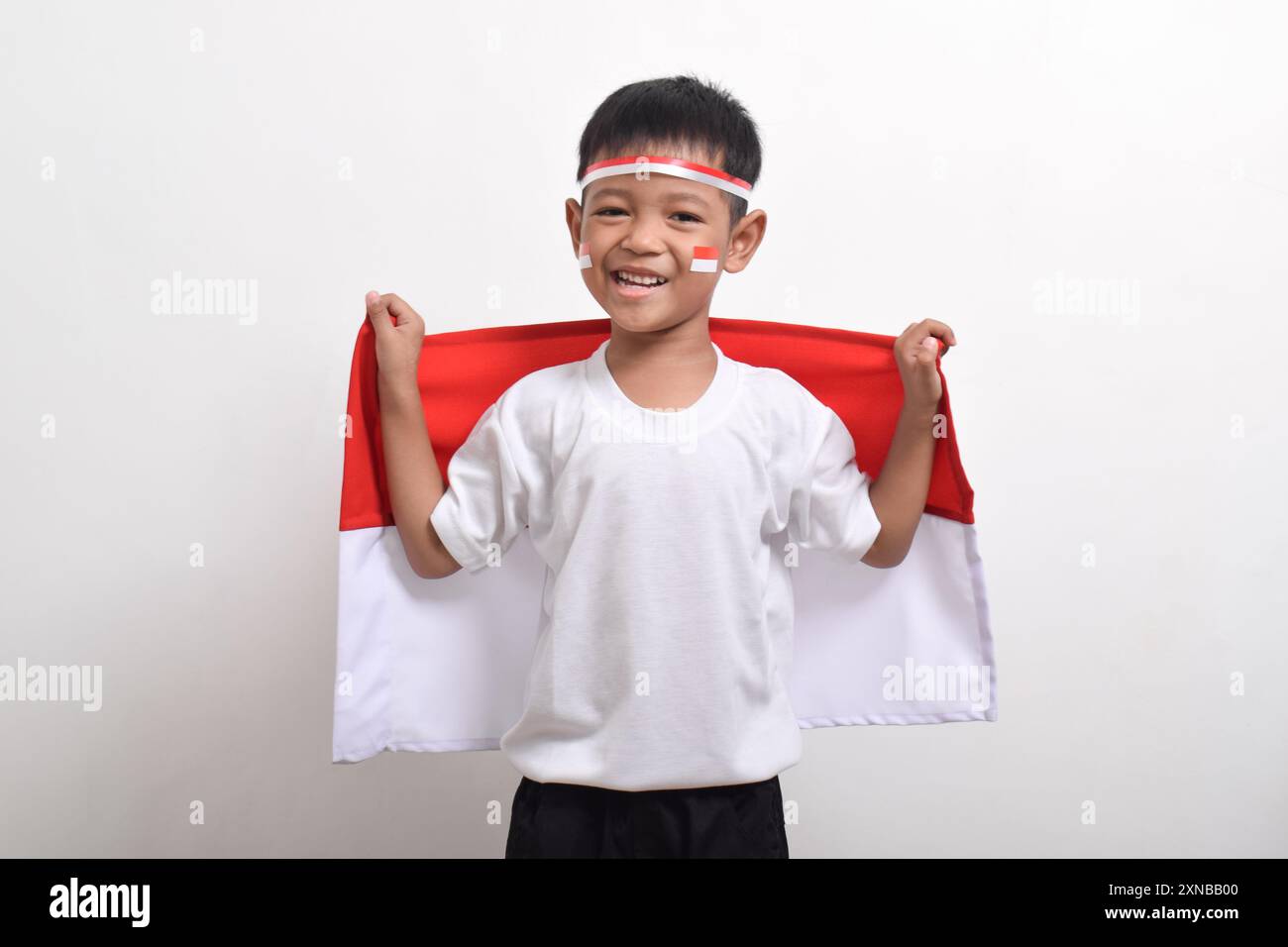 Asian boy wearing flag headband and holding Indonesian flag to ...