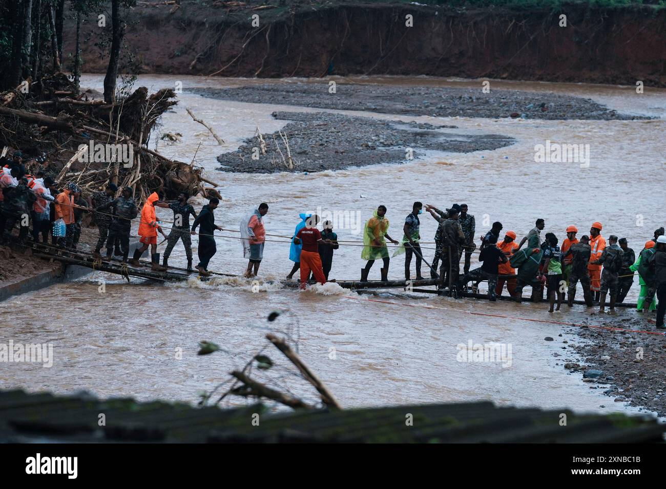 Rescuers use a temporary bridge to cross a river on their second day of ...