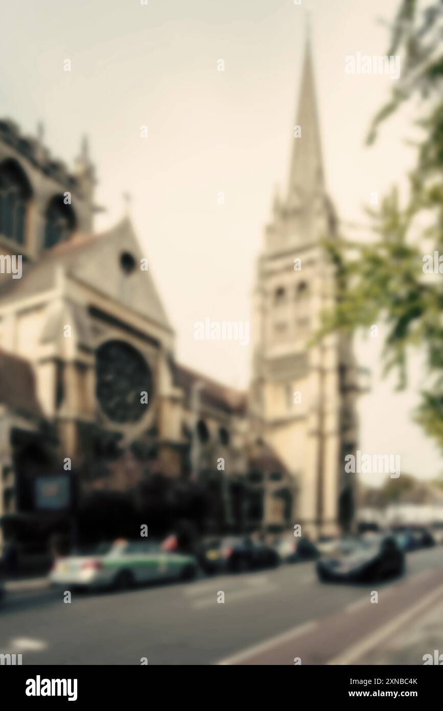A blurred image of a tall church spire and building, with a street and ...