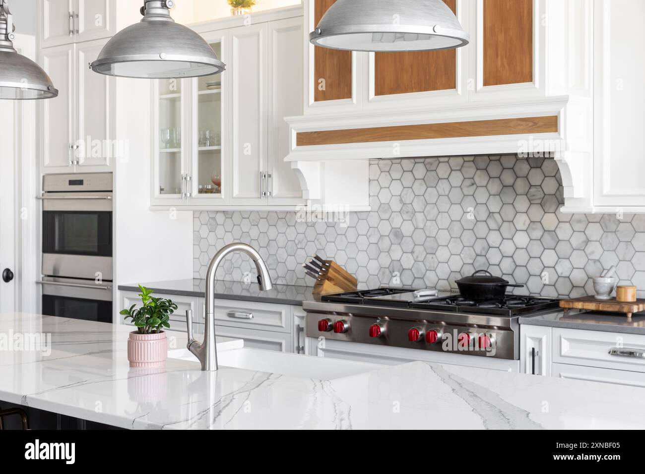 A kitchen sink detail, stainless faucet on a white farmhouse sink and ...