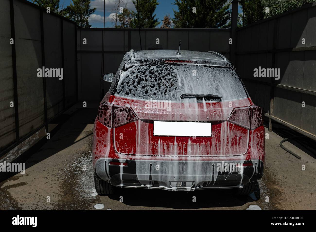 The red coloured car is washed with washing foam at the car wash Stock ...