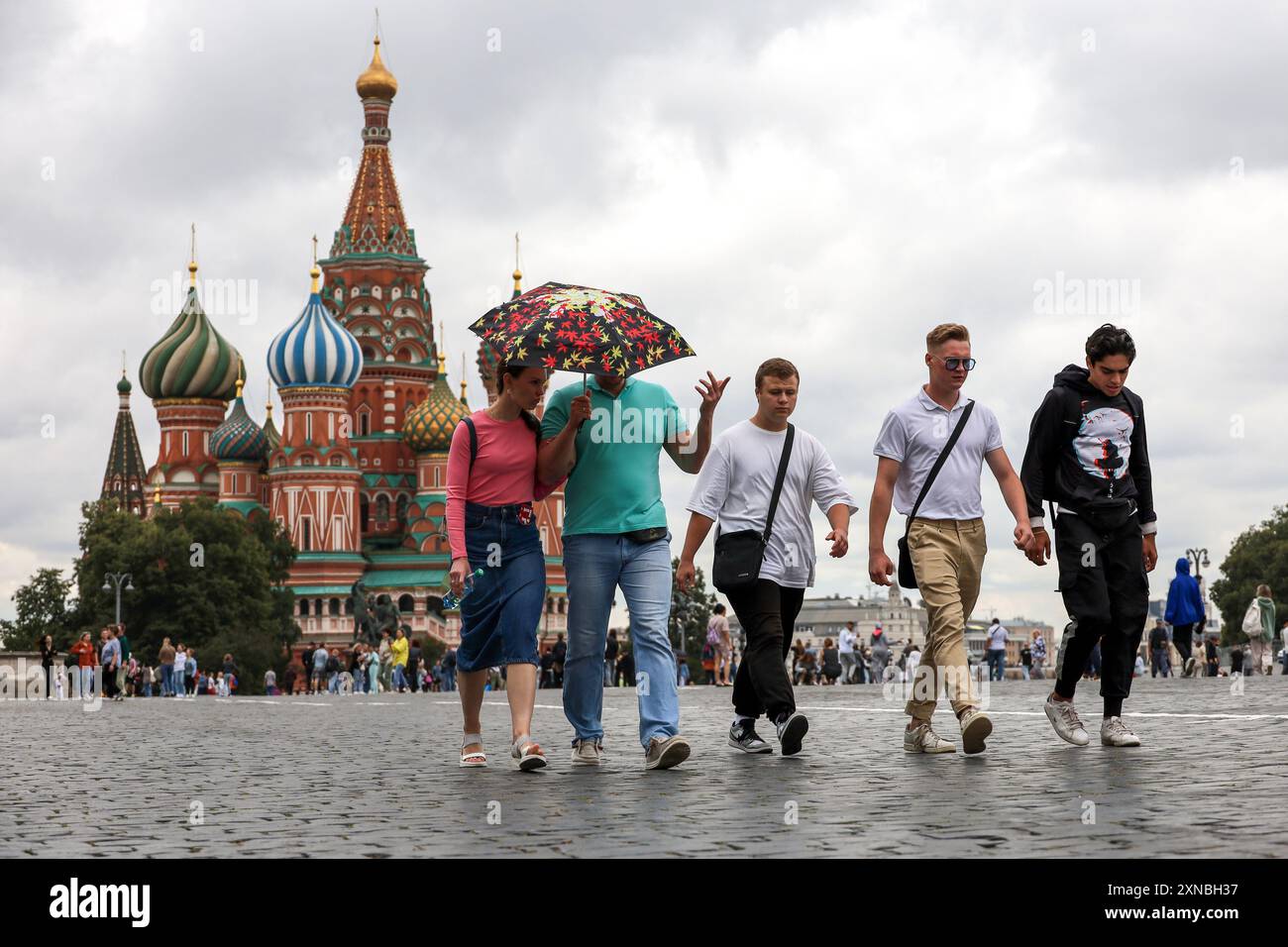 Couple with umbrella walking on the Red Square on background of St ...