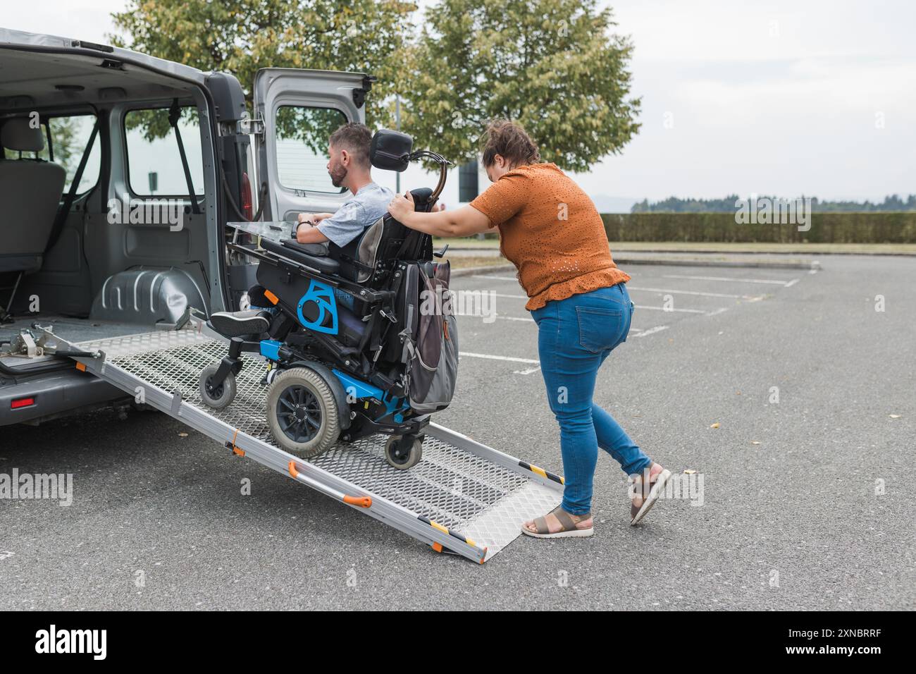 Female assistant helping a man with disability to enter an accessible ...