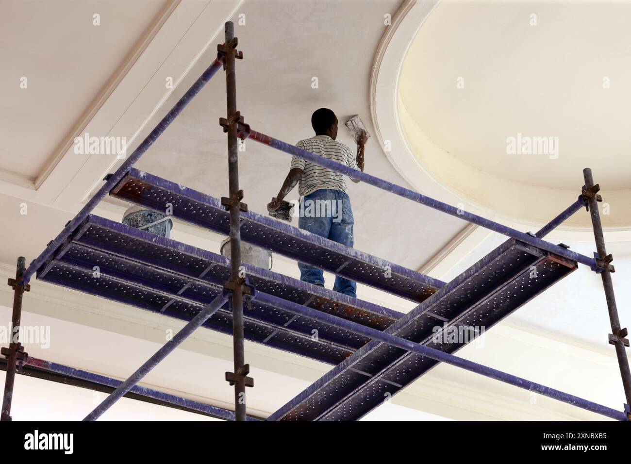 african construction worker climbed on scaffolding plastering a wall ...