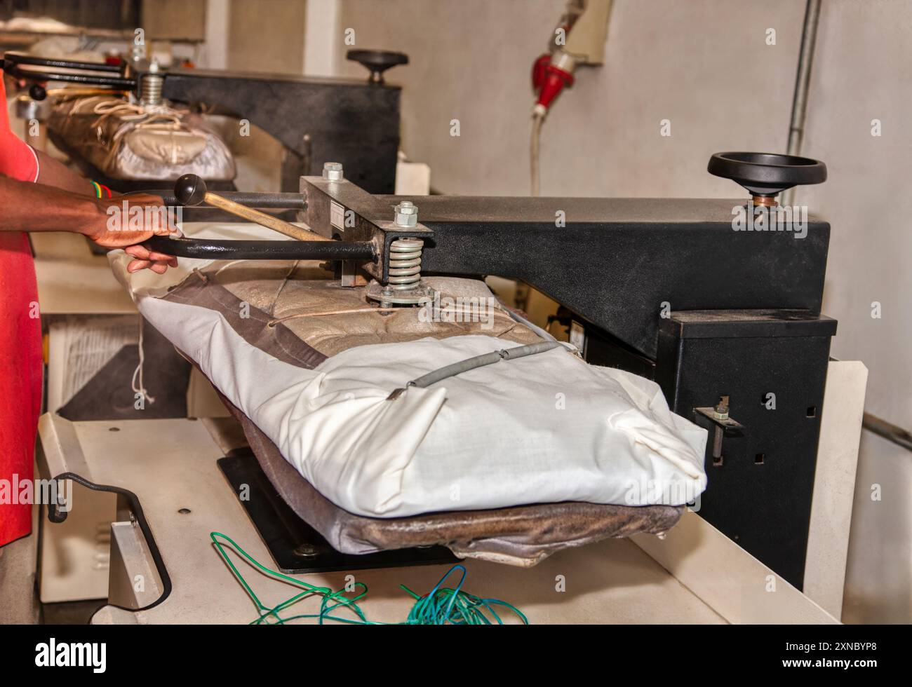 industrial ironing press, african american worker operating the machine ...