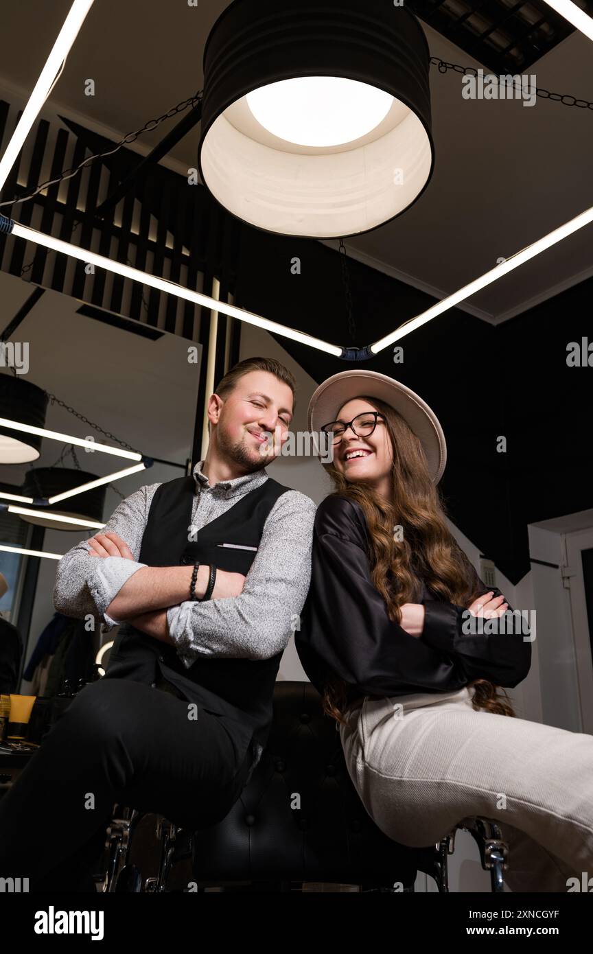 A couple of barbers look at each other sit side by side on a chair in a ...