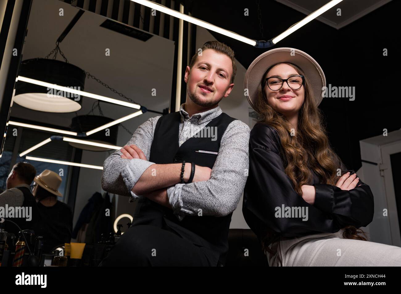 A couple of barbers look at each other sit on a chair in a modern ...