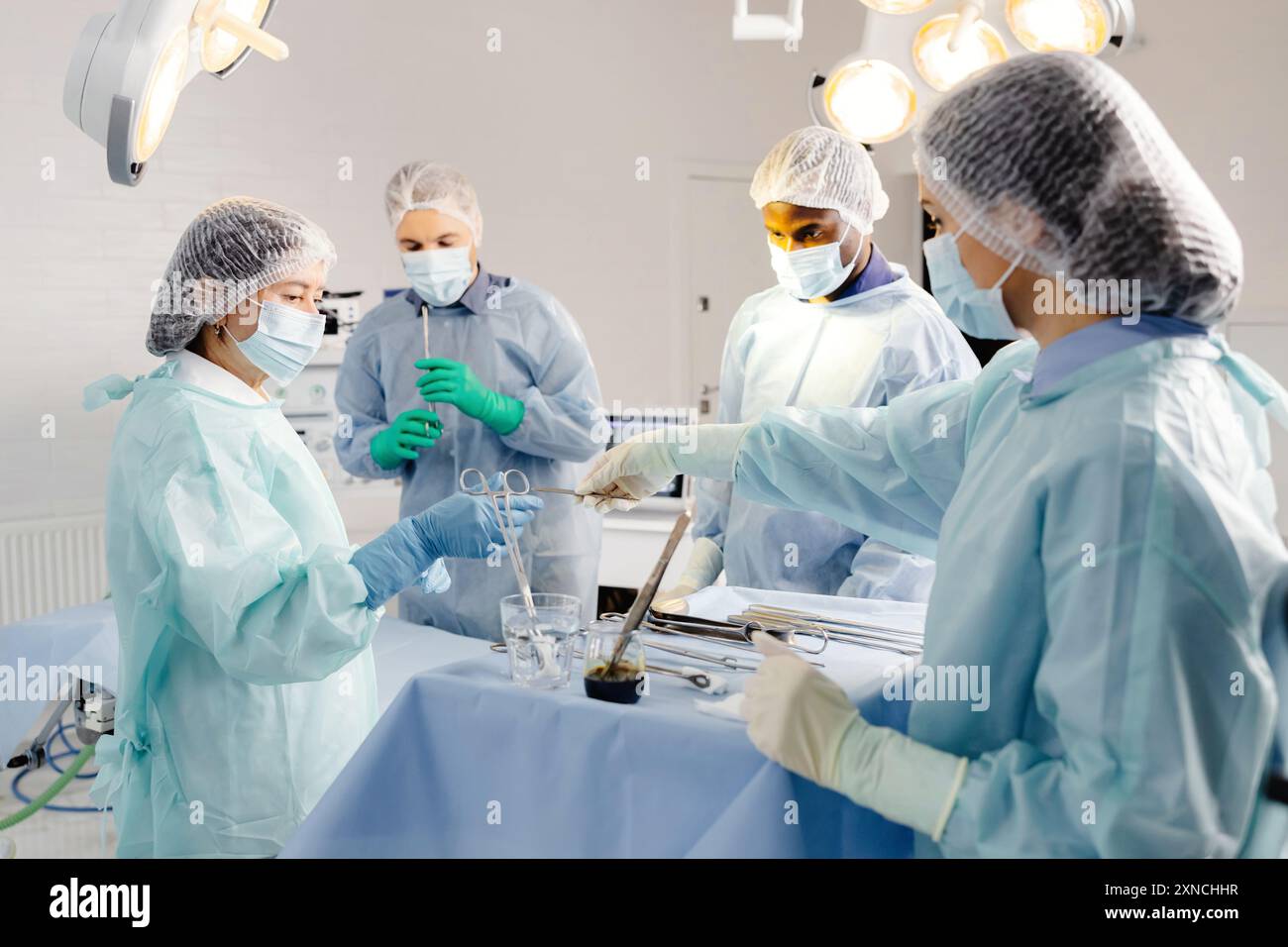 A group of doctors wearing masks are standing together around a table ...
