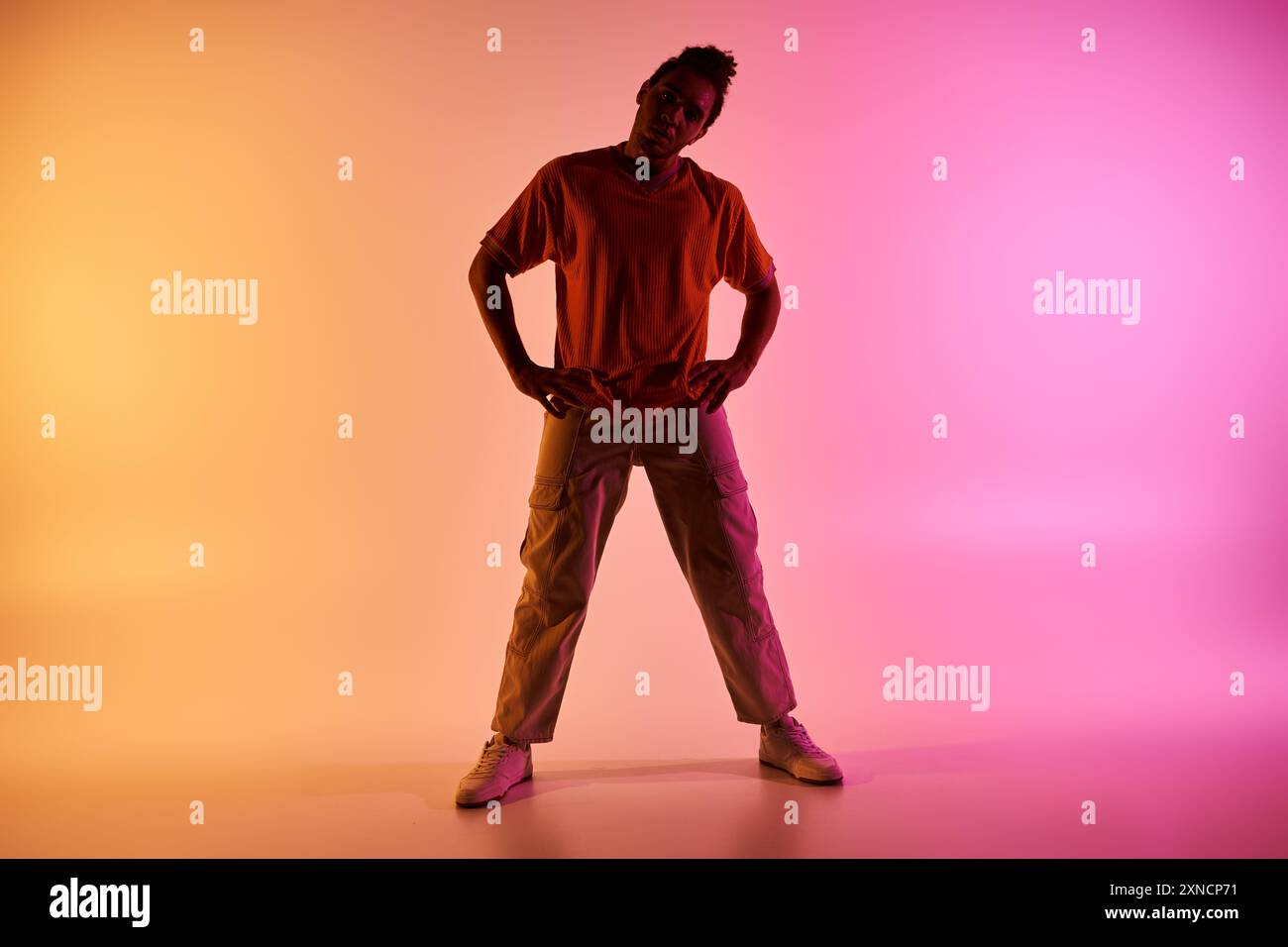 A young African American man poses in a studio setting with colorful ...