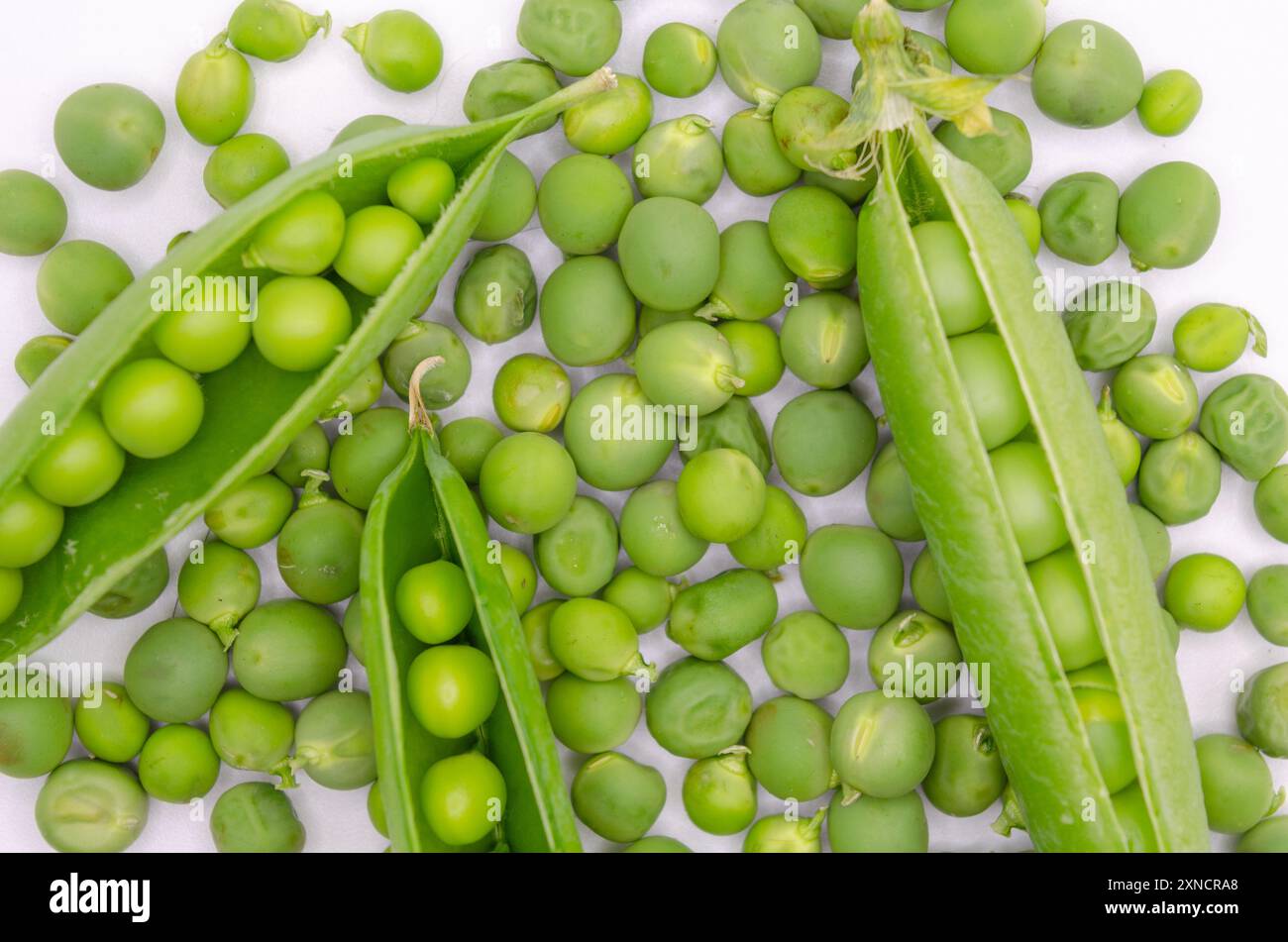 Organic peas and open pea pods on a white background Stock Photo - Alamy
