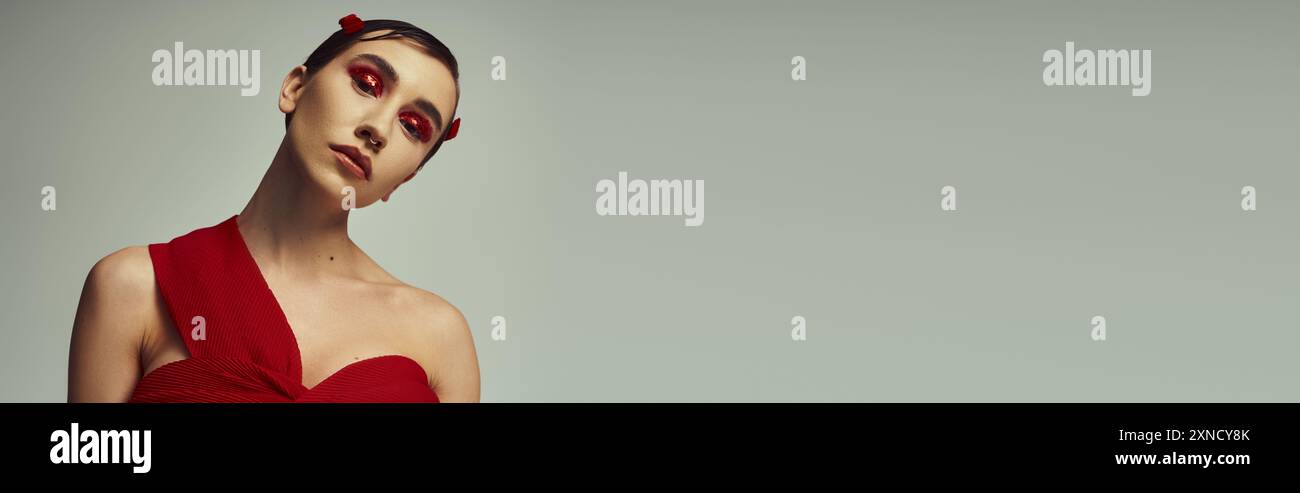 A young woman with short hair and bold red eyeshadow poses in a red ...