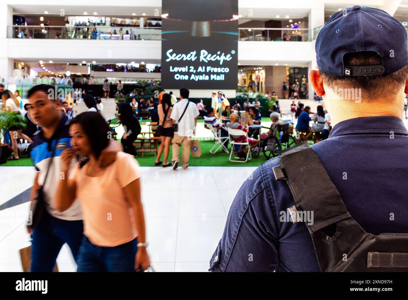 Philippino security guard watching over customers in Greenbelt shopping mall, Makati, Manila ...
