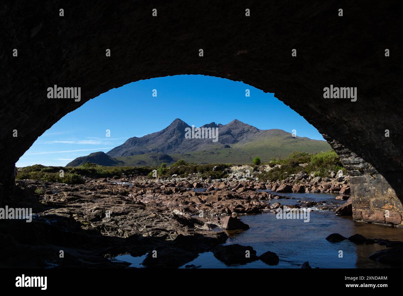 Black Cuillin ridge and landscape viewed through the arch of a bridge ...
