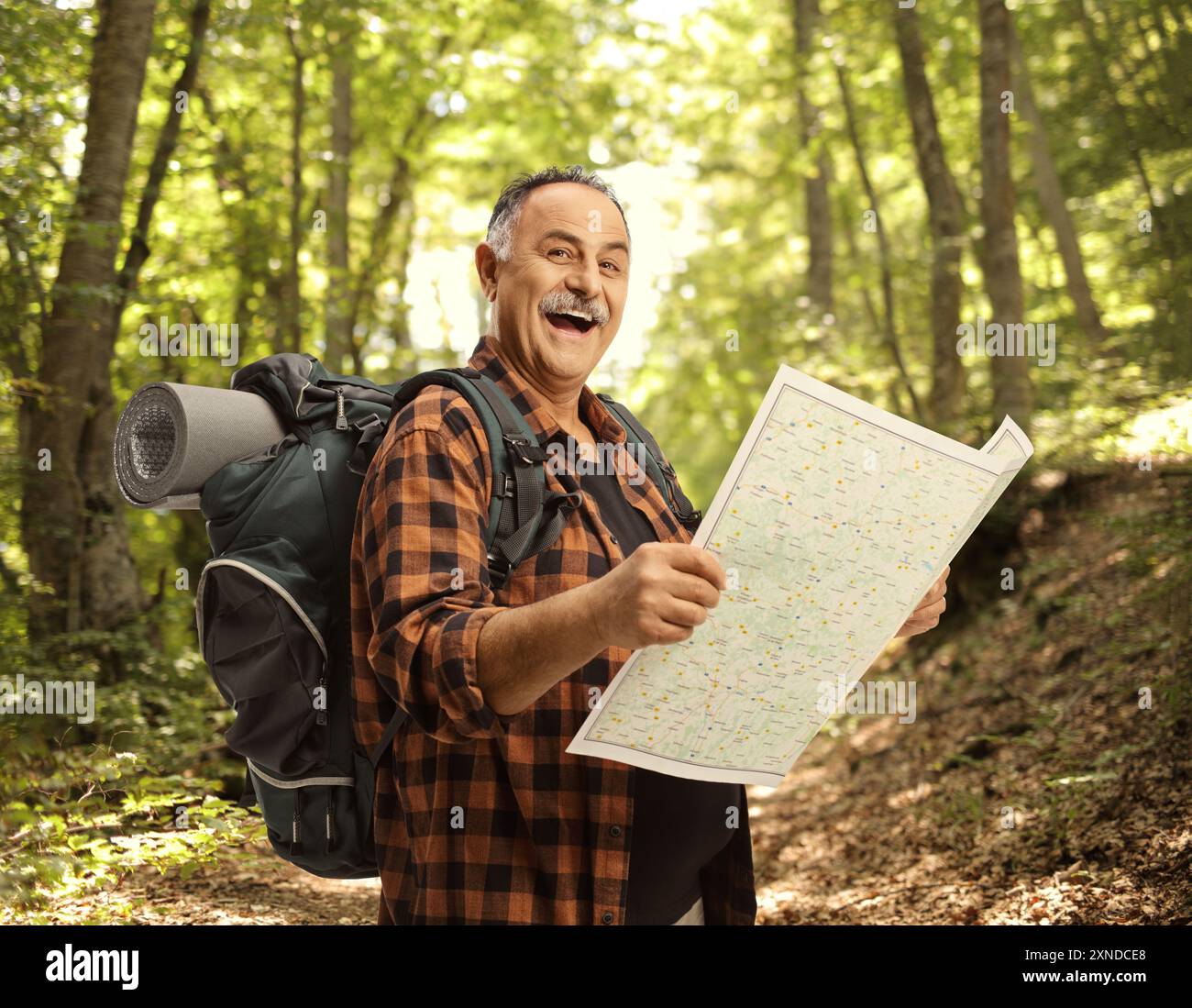 Smiling mature hiker holding a map in a forest Stock Photo - Alamy