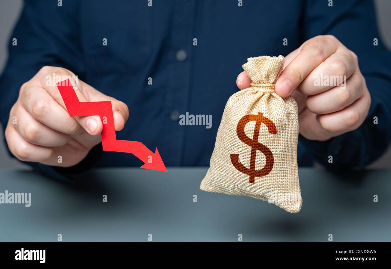 A man holds a red arrow pointing down near a dollar money bag ...