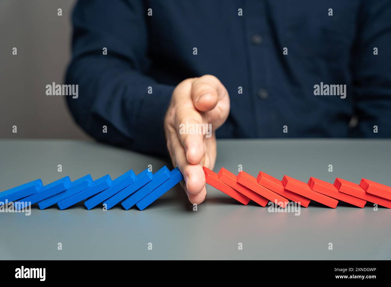A man stops two domino chains from colliding. The concept of stopping a ...