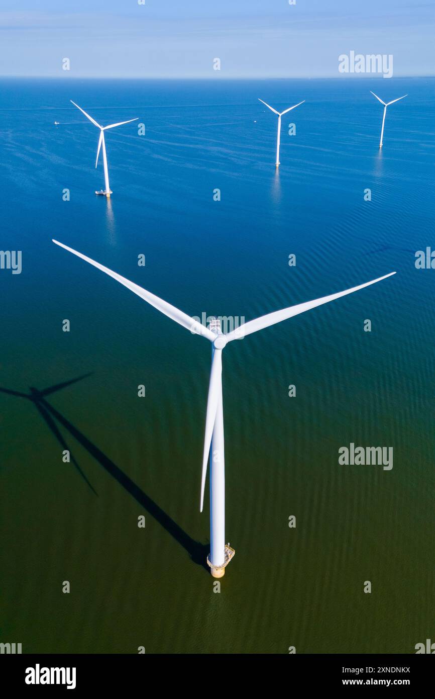 Tall wind turbines spin gracefully, converting wind into clean energy amidst the serene waters ...