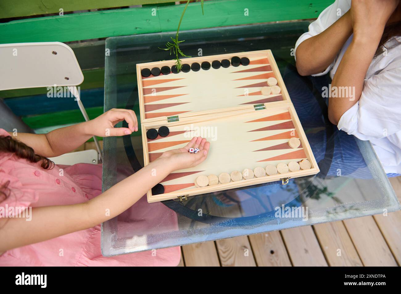 Two children enjoying an outdoor game of backgammon. The image captures ...