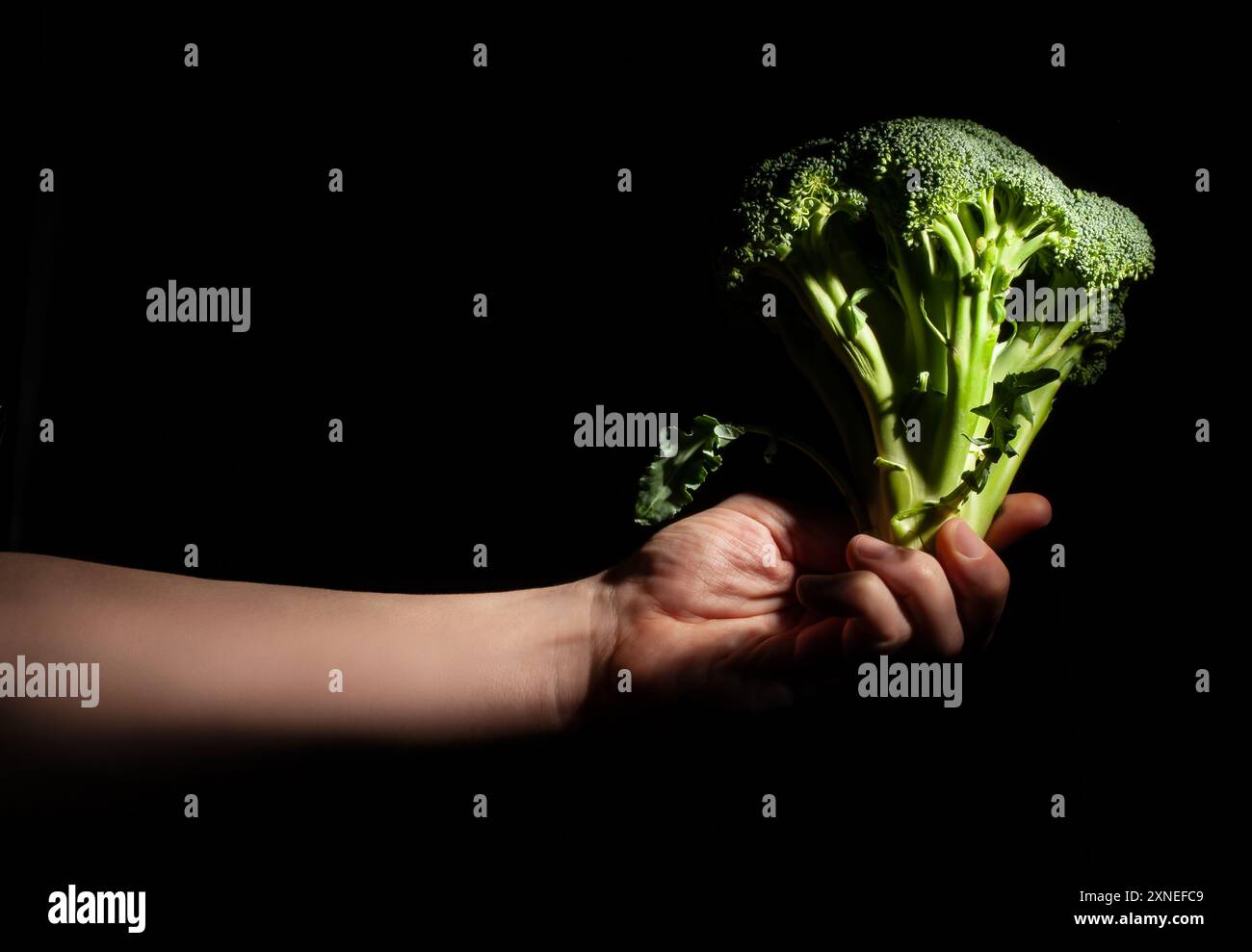 broccoli in hand on black background Stock Photo - Alamy