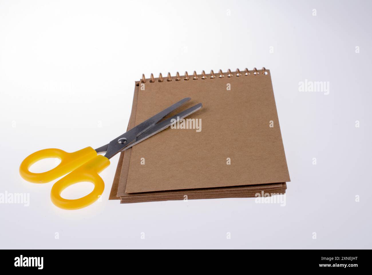 spiral notebook and scissors on a white background Stock Photo - Alamy