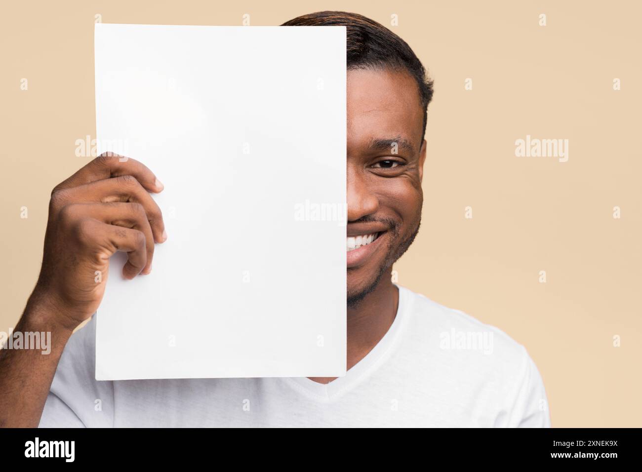 Man Covering Half Of Face With Paper Sheet In Studio Stock Photo - Alamy