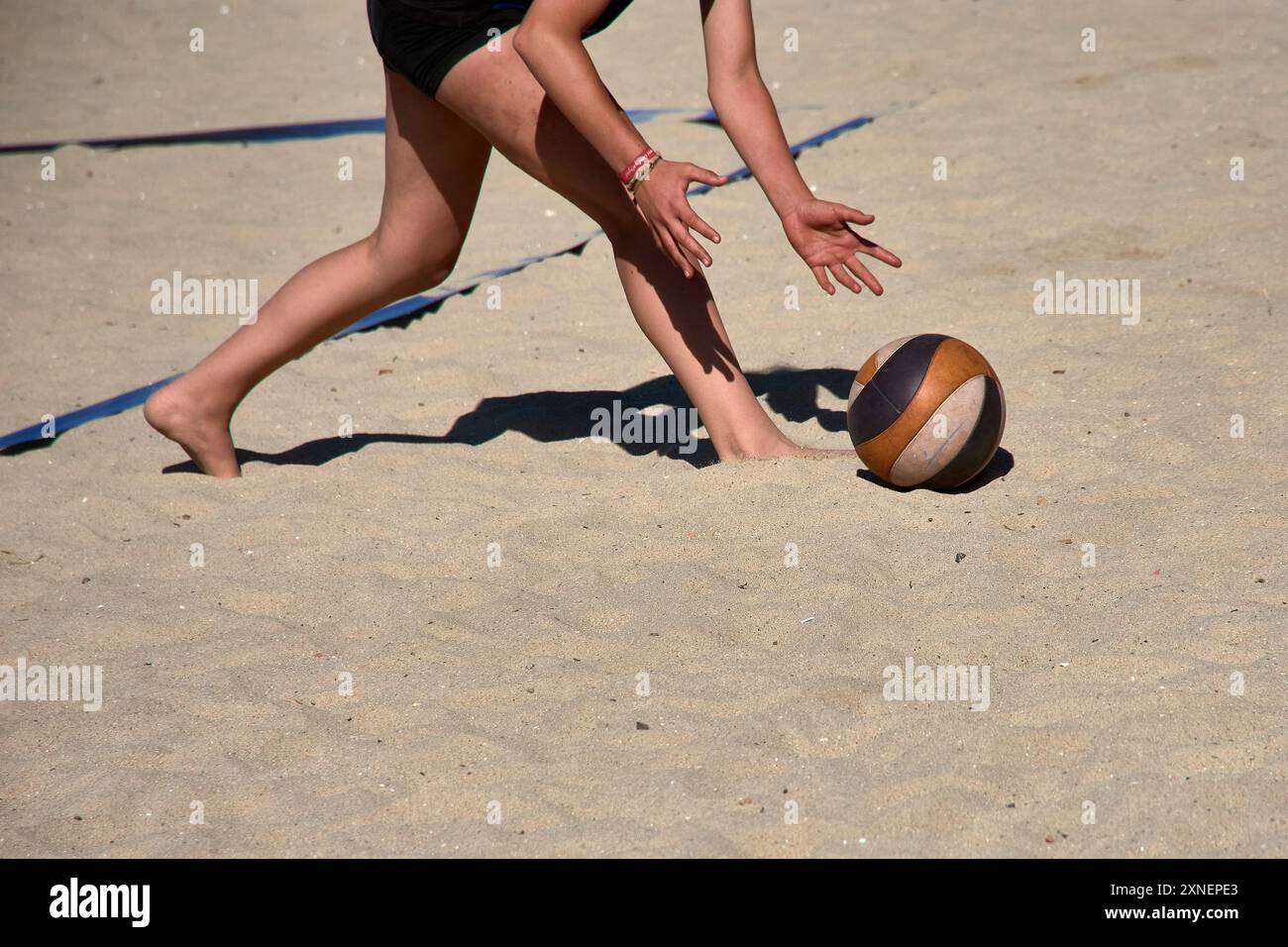 A beach volleyball player collects the ball after a highly contested ...