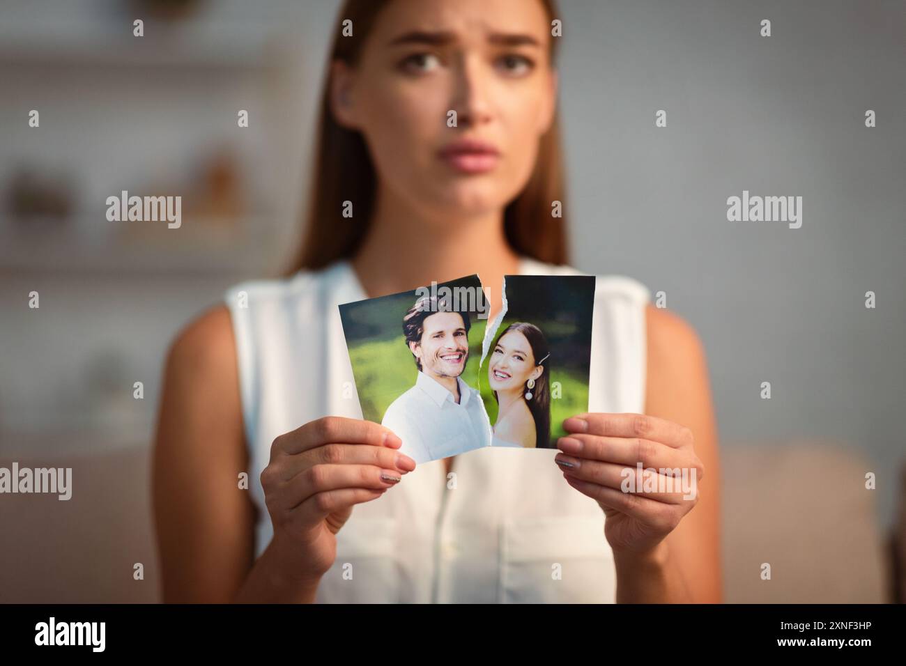 Sad Girl Ripping Photo With Ex-Husband Indoor Stock Photo - Alamy
