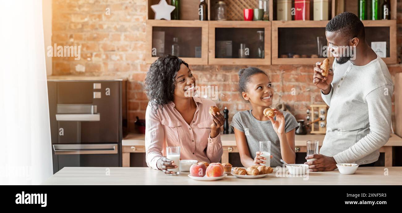Friendly young family having conversation during breakfast at kitchen ...
