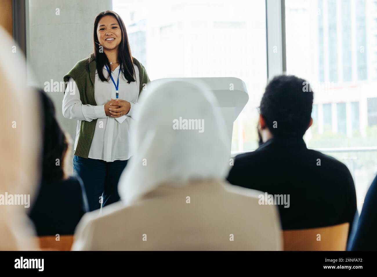 A woman displaying leadership while giving a talk at a business conference event. Engaging ...