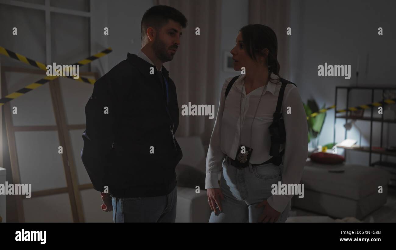 A man and woman, possibly detectives, stand in a dimly lit crime scene ...
