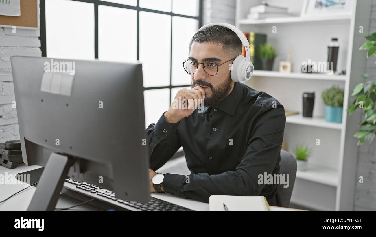 Handsome bearded man with headphones working in a modern office setup ...
