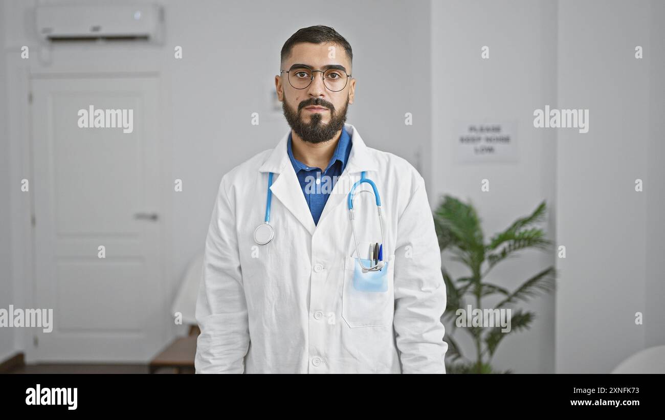 Confident male doctor with beard standing in a white clinic corridor ...