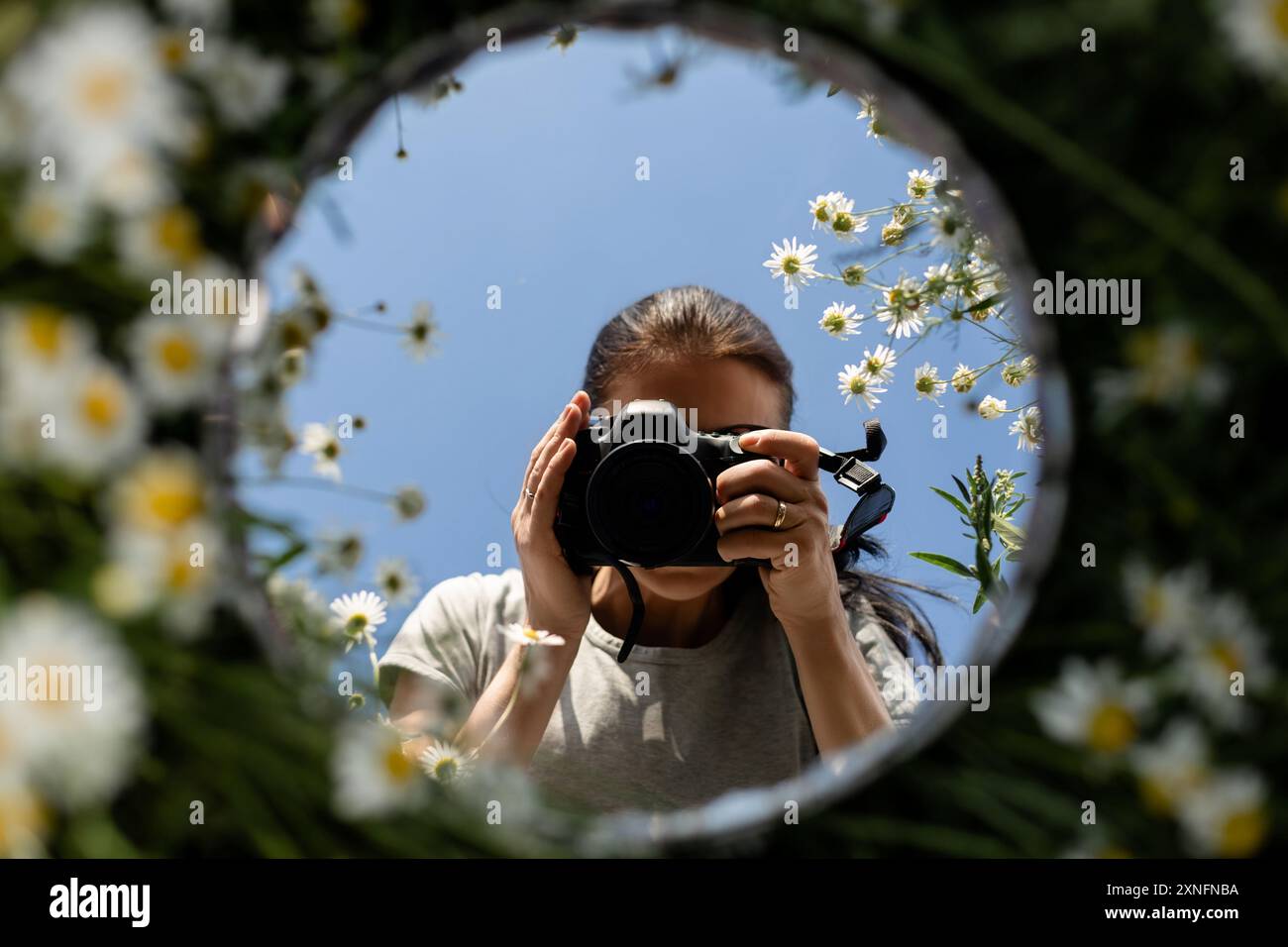 A female photographer takes a picture of herself in the mirror. Photo ...