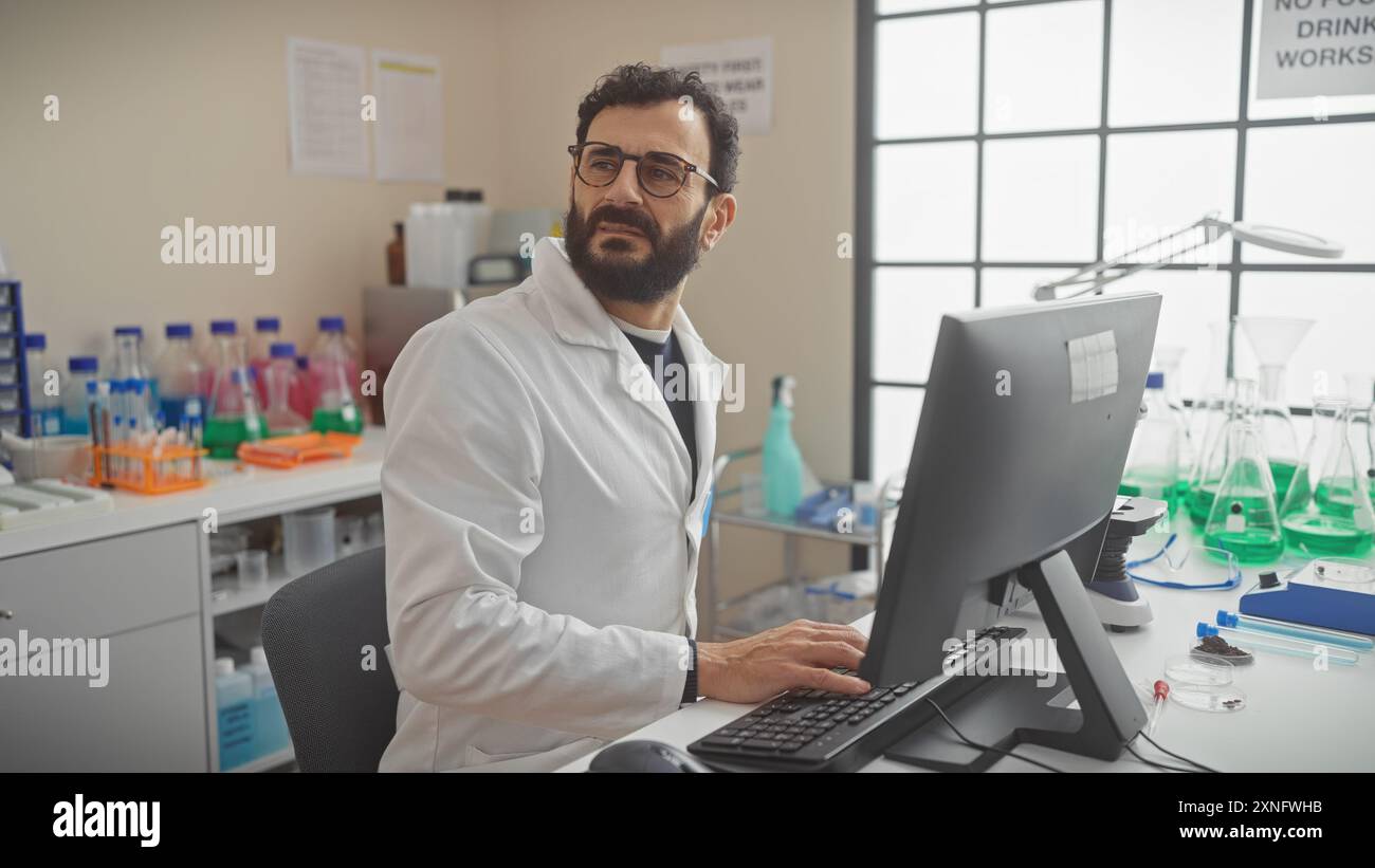 Bearded scientist man in laboratory working with computer, wearing ...
