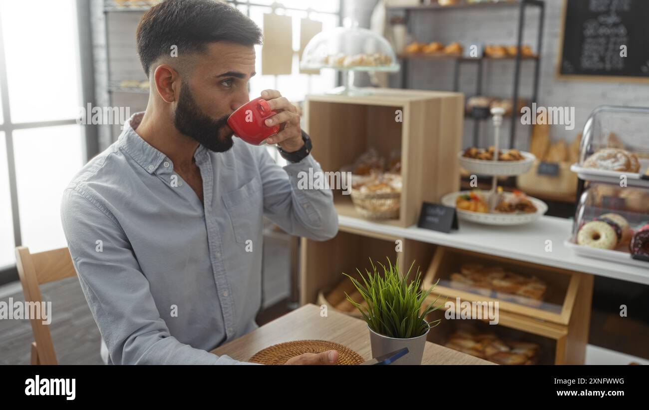 Handsome young hispanic man with a beard drinking coffee in a cozy ...