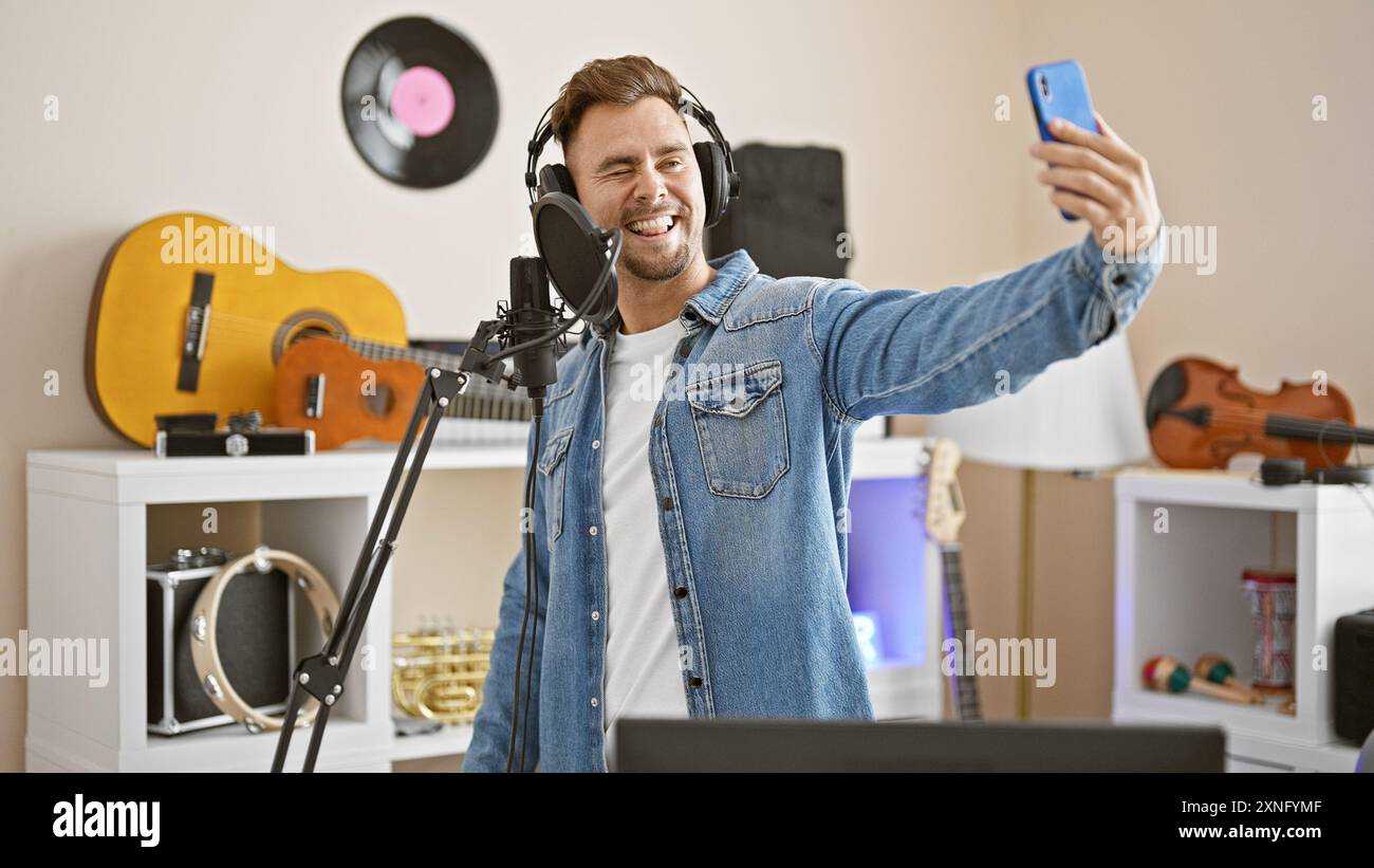 A cheerful man takes a selfie in a home music studio surrounded by ...