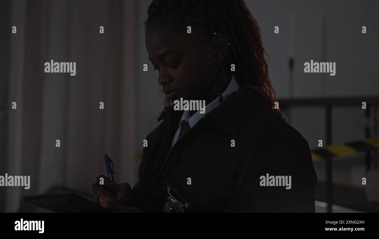 African american woman detective writing at a dimly lit indoor crime ...