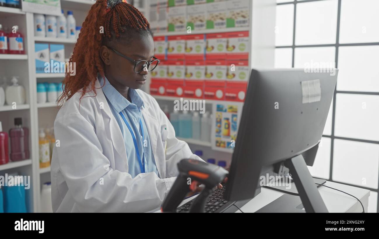 A young african american woman pharmacist works at a computer in a ...