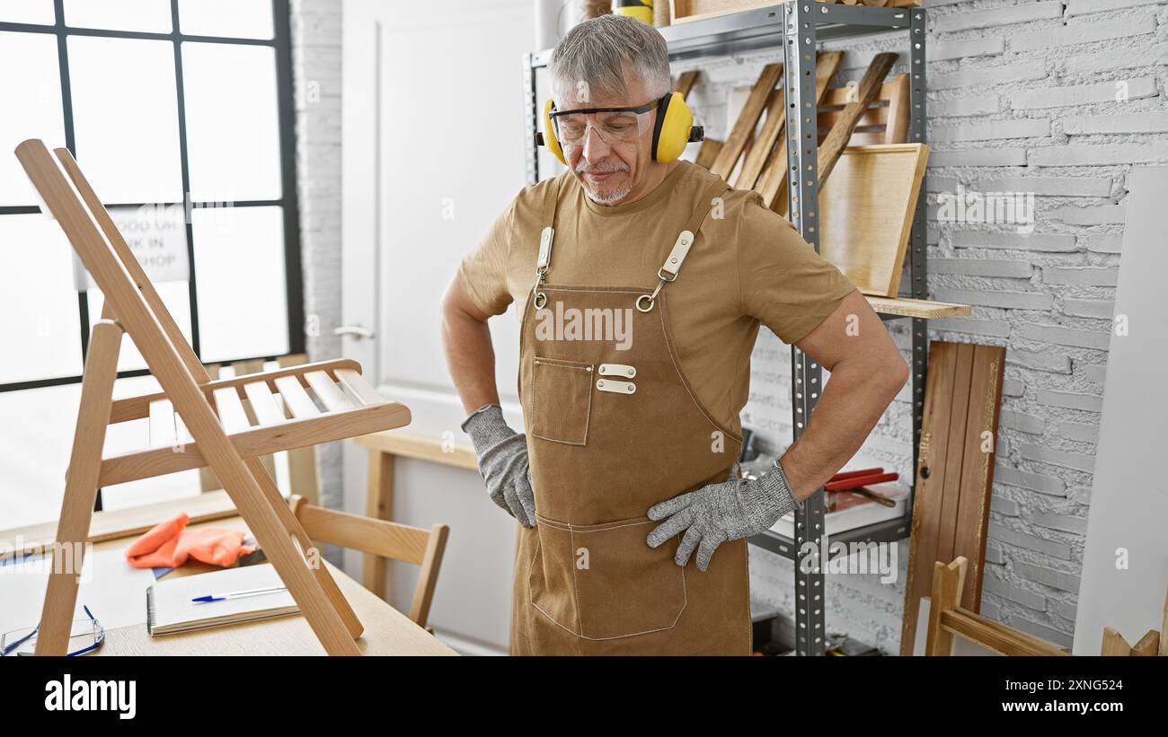 Senior man in apron poses confidently in a well-equipped carpentry ...
