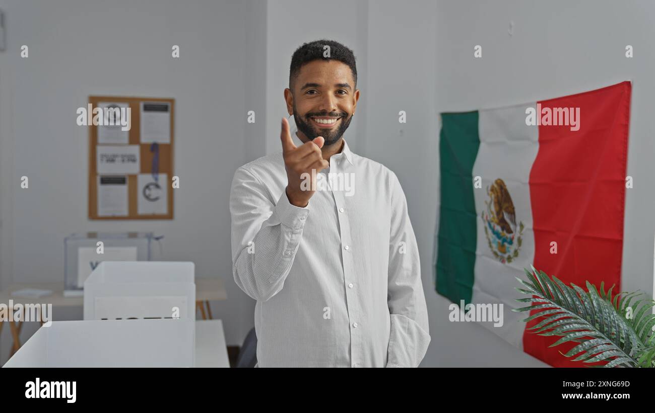 A cheerful young man pointing at the camera, with a mexican flag in a ...